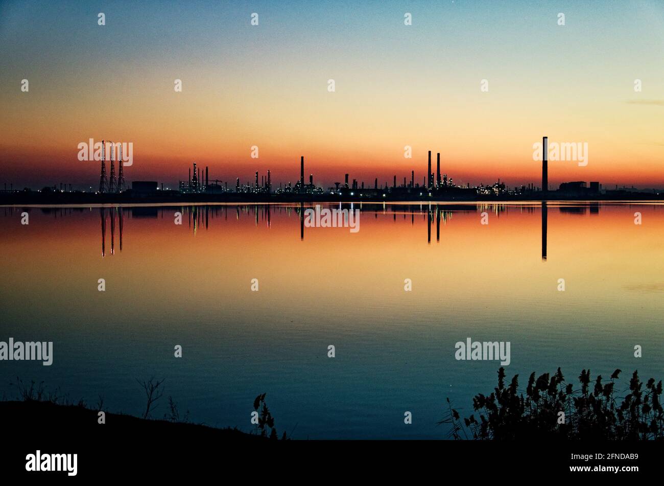 An illuminated oil and gas refinery plant at sunset in Navodari ...