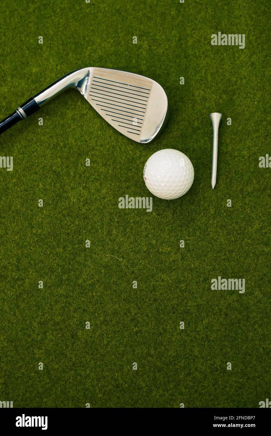 A vertical shot of a golf club, ball, and a tee on the grass with a ...
