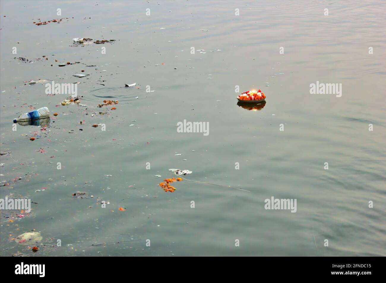 Diya floating on a river amongst empty plastic bottle. water pollution ...