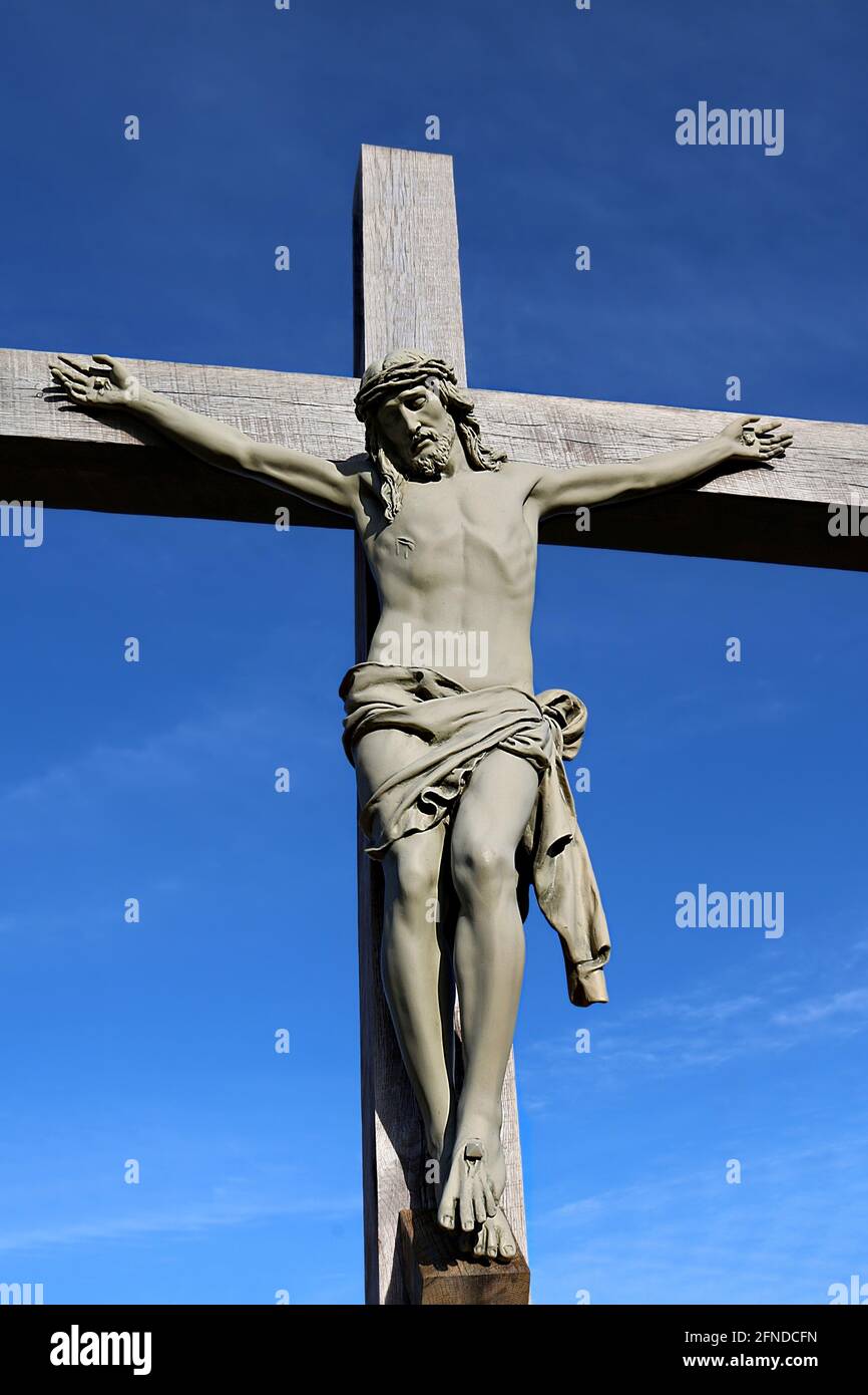 A low-angle shot of the statue of the Crucifixion of Jesus Christ against the blue sk Stock ...