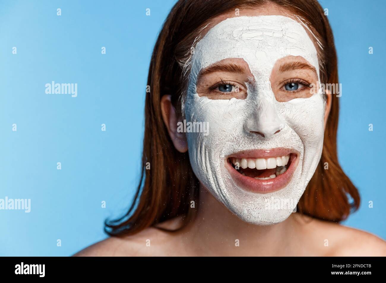 Young girl with facial mask looking at camera over white background ...