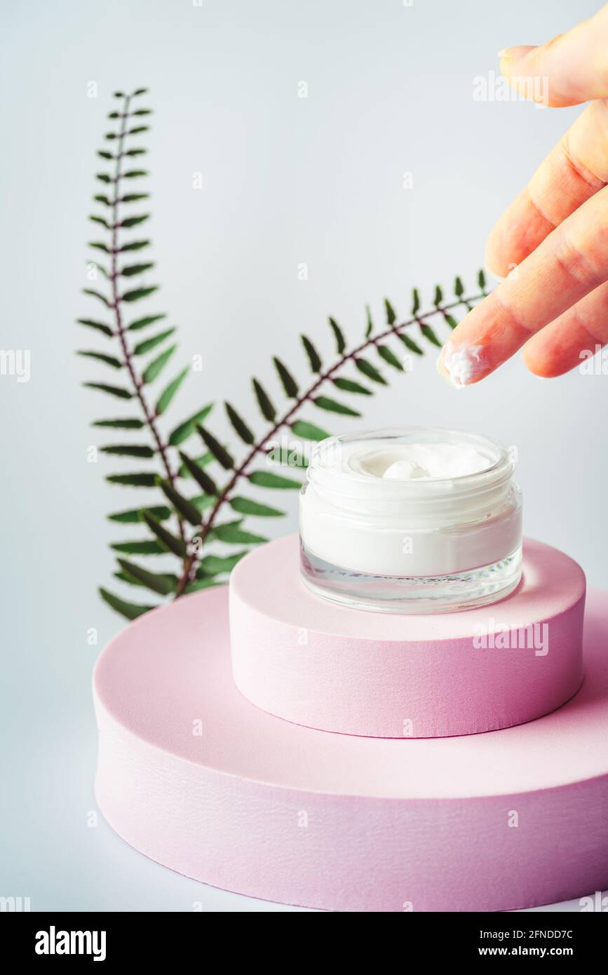 Glass jar with natural moisturizer face cream on special pink podium ...
