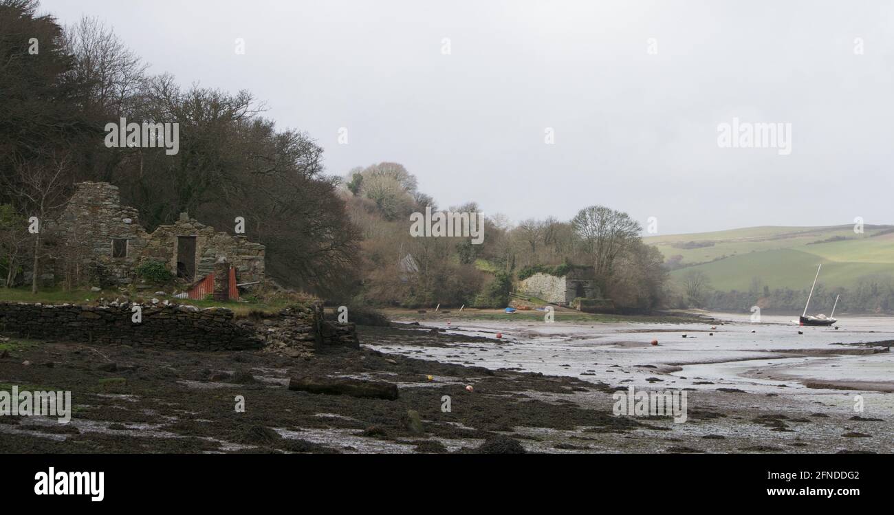 Muddy, tidal estuary at low tide. Green fields and rolling hills in the ...