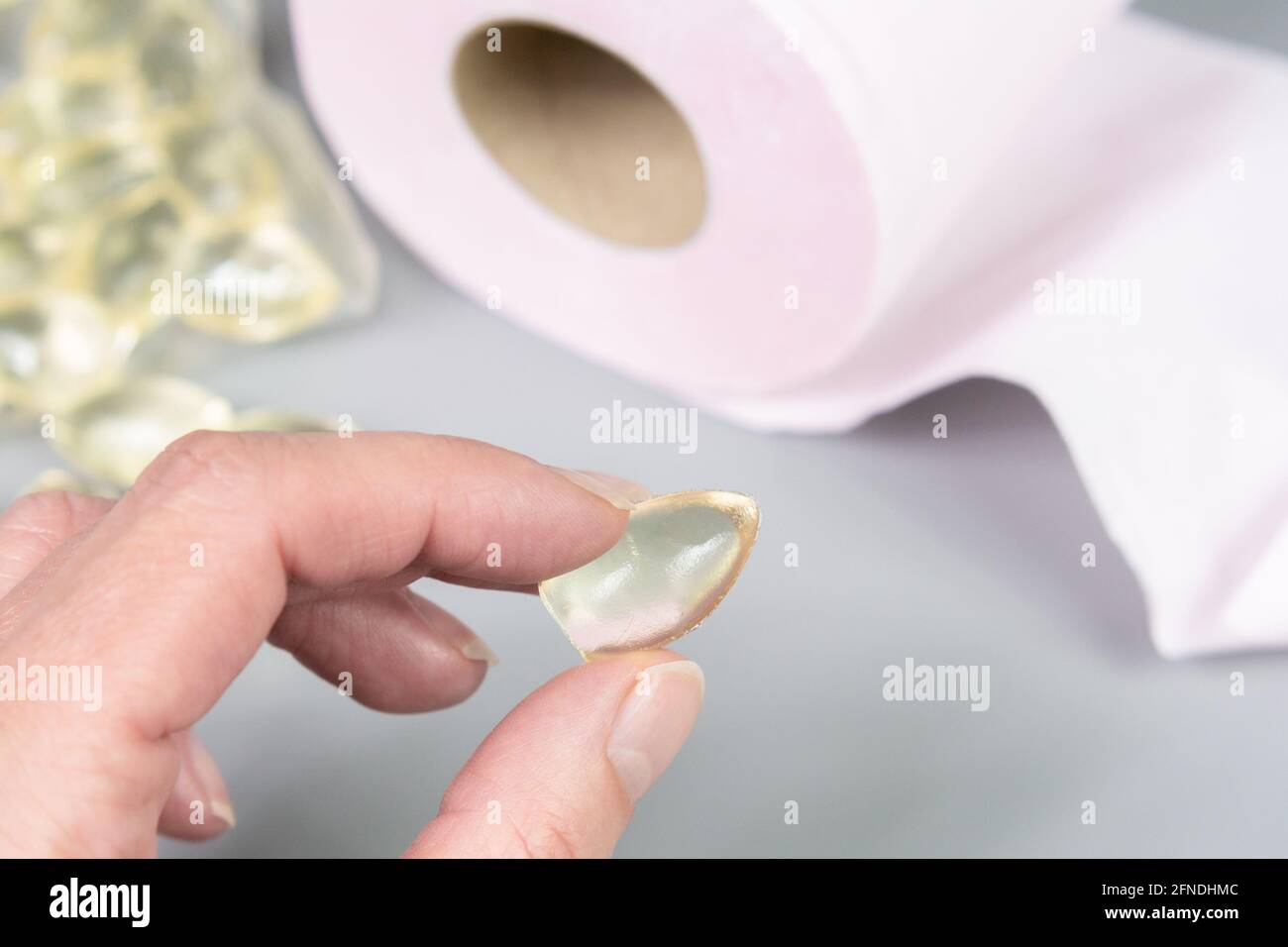 Woman's hand holding glycerin suppository, toilet paper and ...