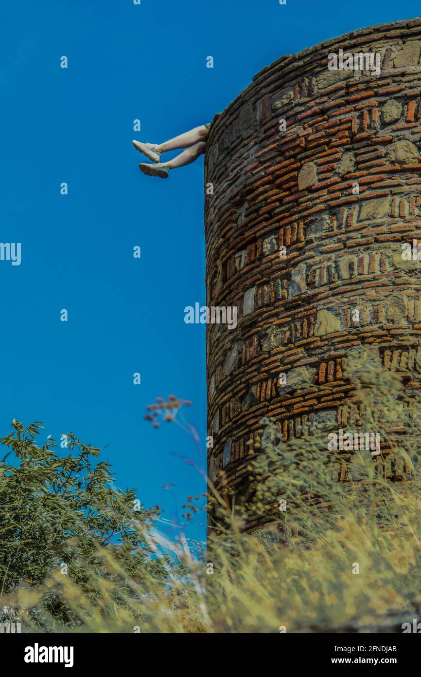 Womans legs kicking out into the air from top of ancient castle wall ...