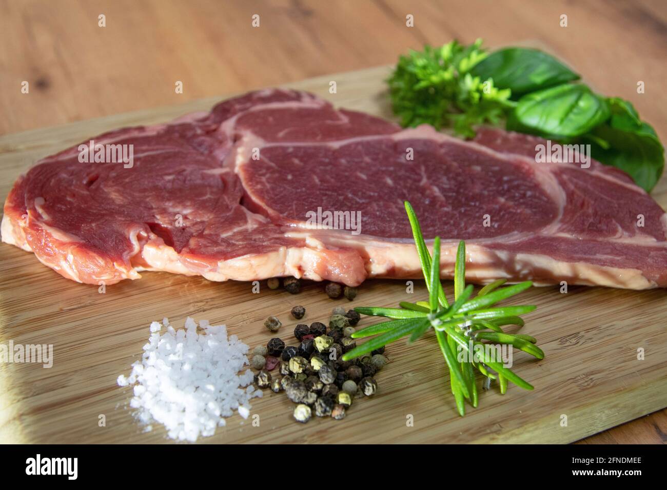 Raw entrecote steak with salt, pepper, basil, parsley and rosemary ...