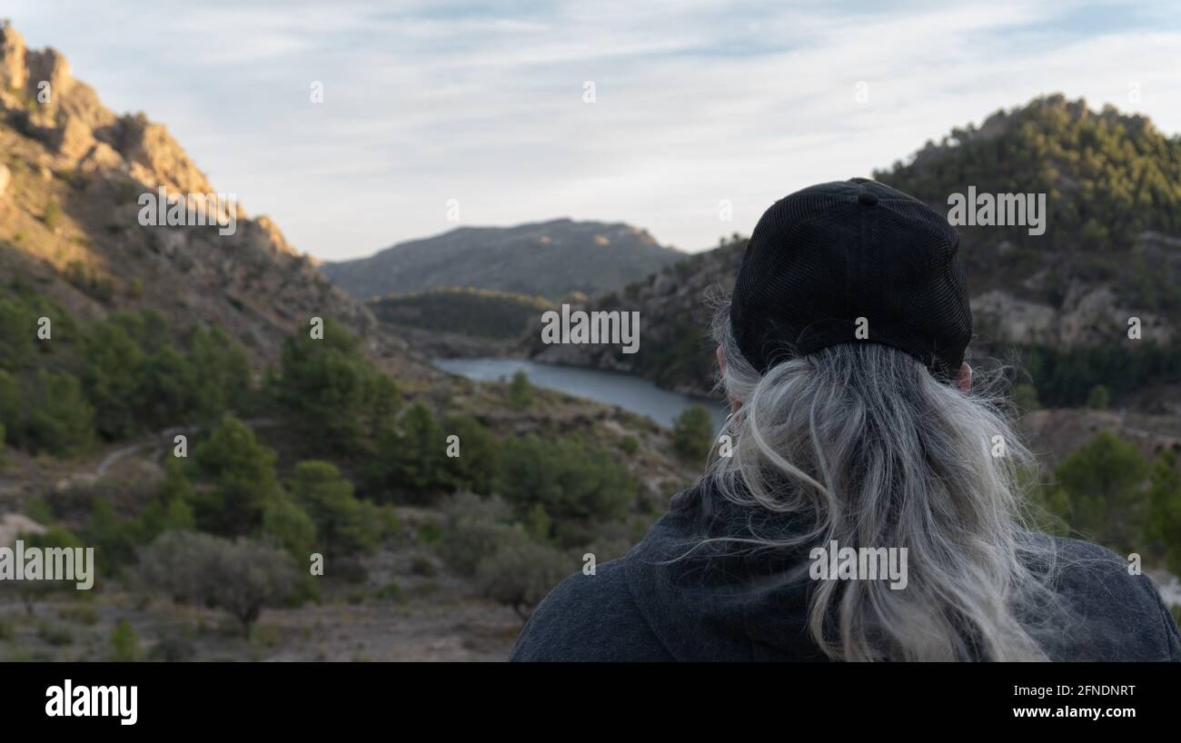 A woman from behind wearing a black cap and admiring a beautiful ...