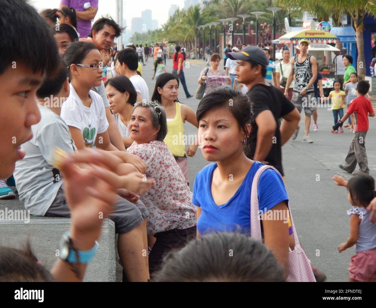 Filipino visitors walk and sit near the waterfront behind Mall of Asia ...