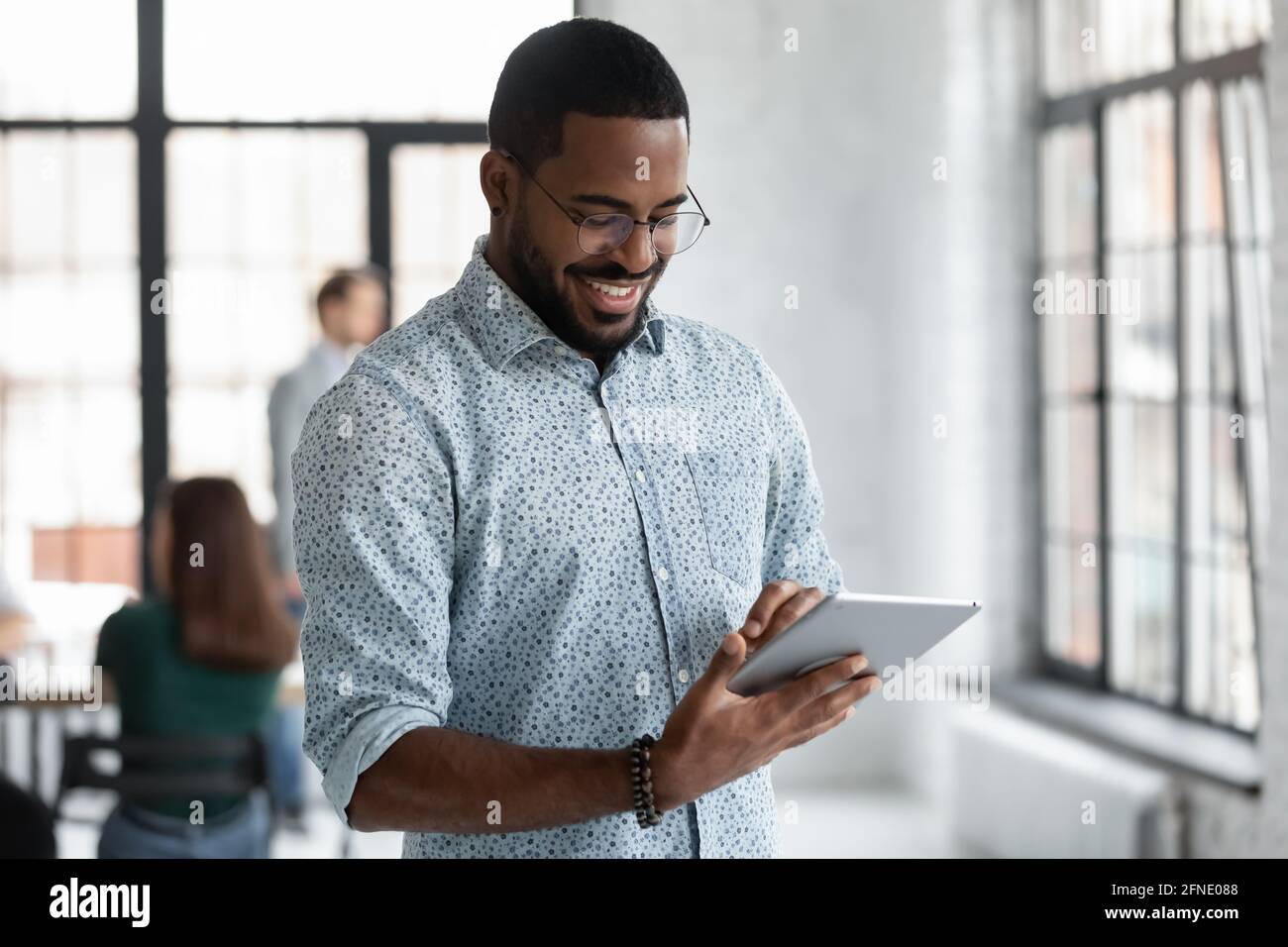 Happy Black male employee reading on digital device screen Stock Photo ...