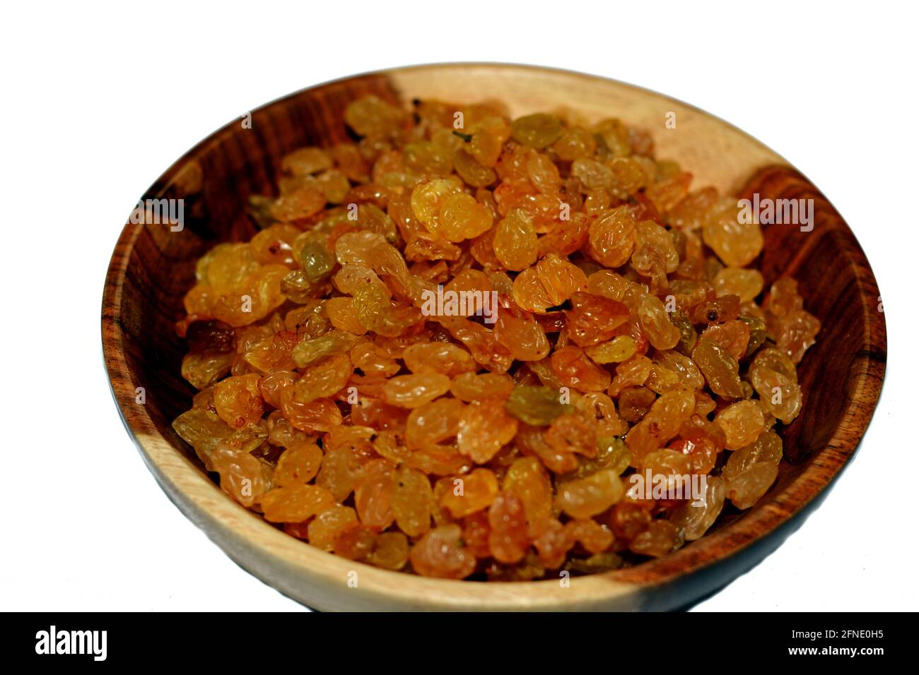 Dried raisins in a brown wooden bowl isolated on a white background ...
