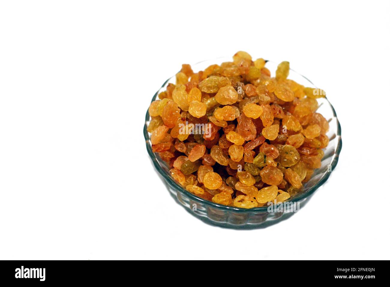 Dried raisins in a brown wooden bowl isolated on a white background ...