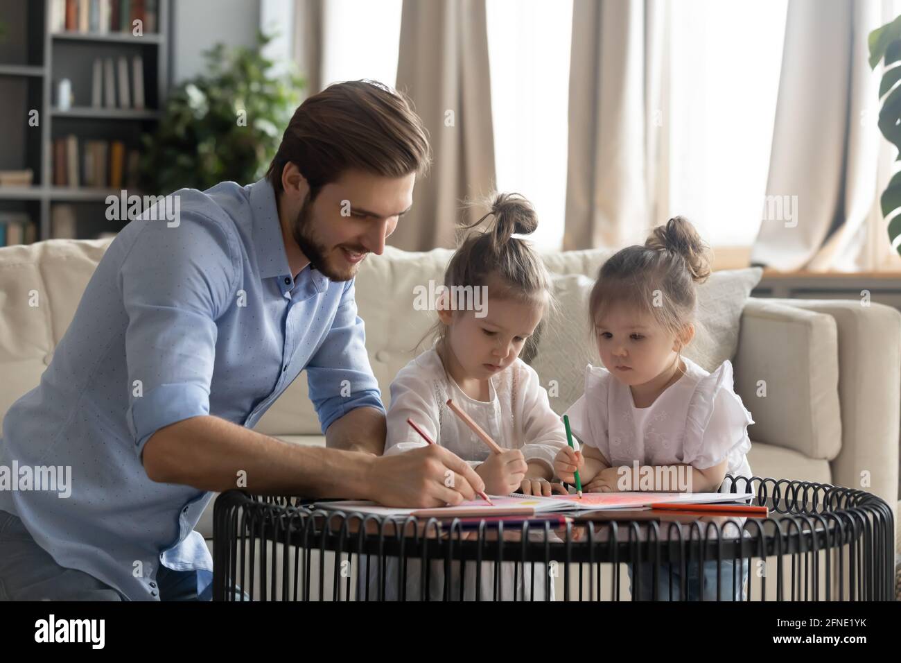 Caring dad drawing in album with small daughters Stock Photo - Alamy