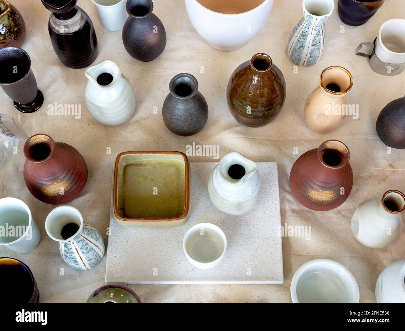 Various colorful ceramic vase arranged on white calico fabric, top view ...