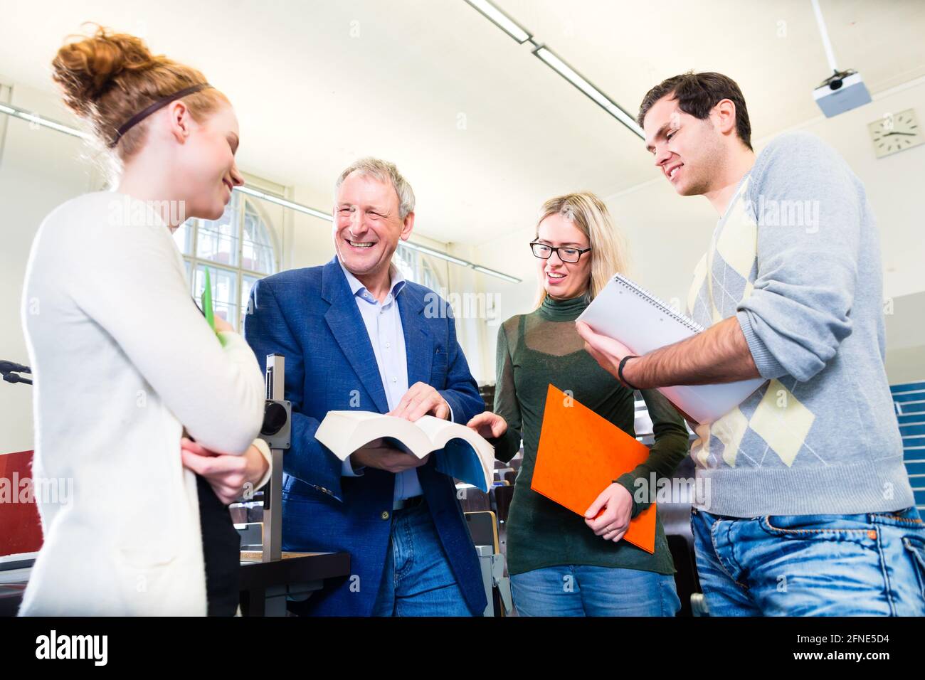 College students making lesson notes while asking professor in ...