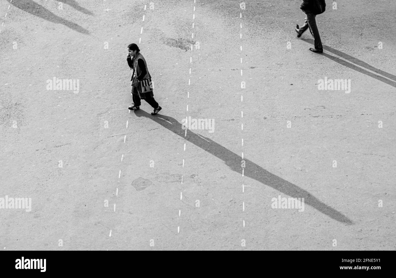 people walking on road maintain social distance with dramatic shadow ...