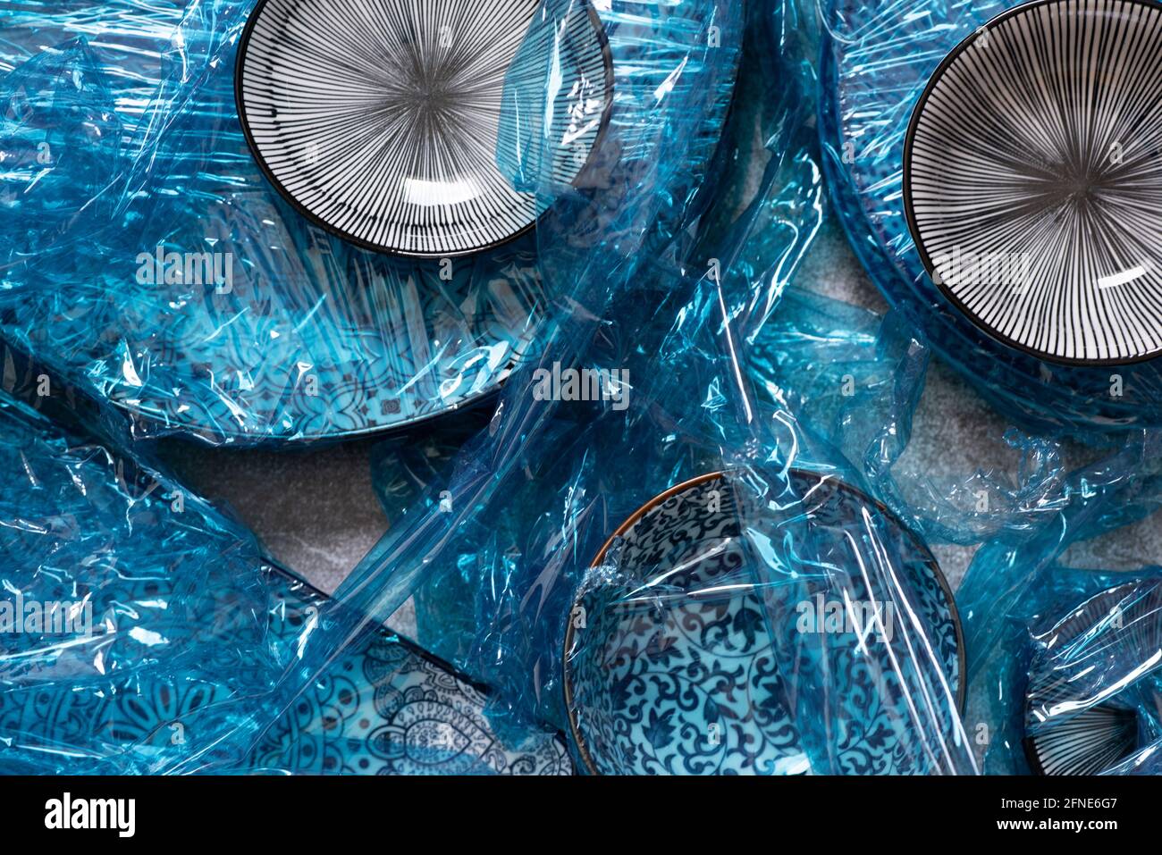 Small plates wrapped in blue cling film placed on brown wooden floor ...