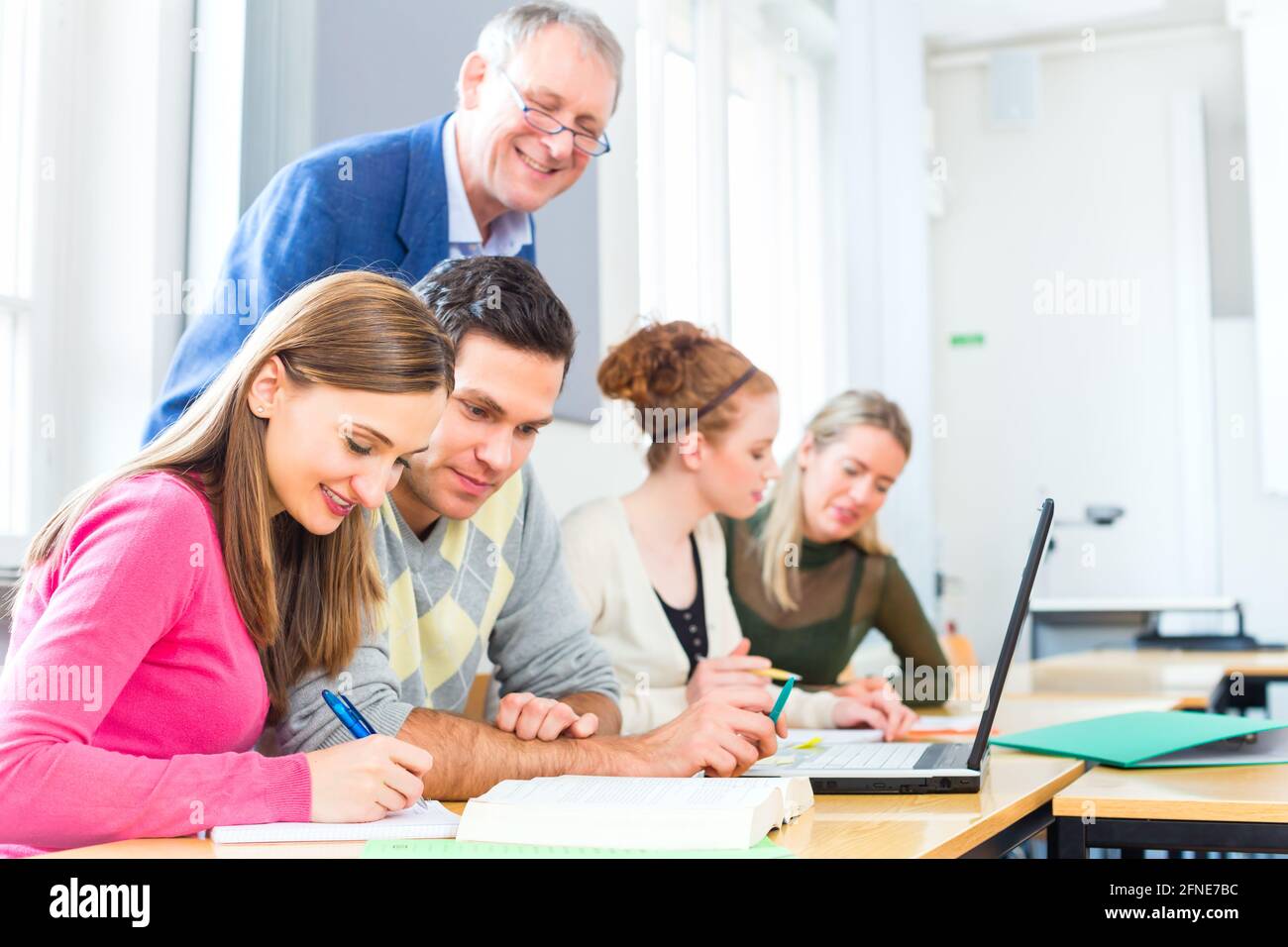 Group of students learning at college supervised by professor Stock ...