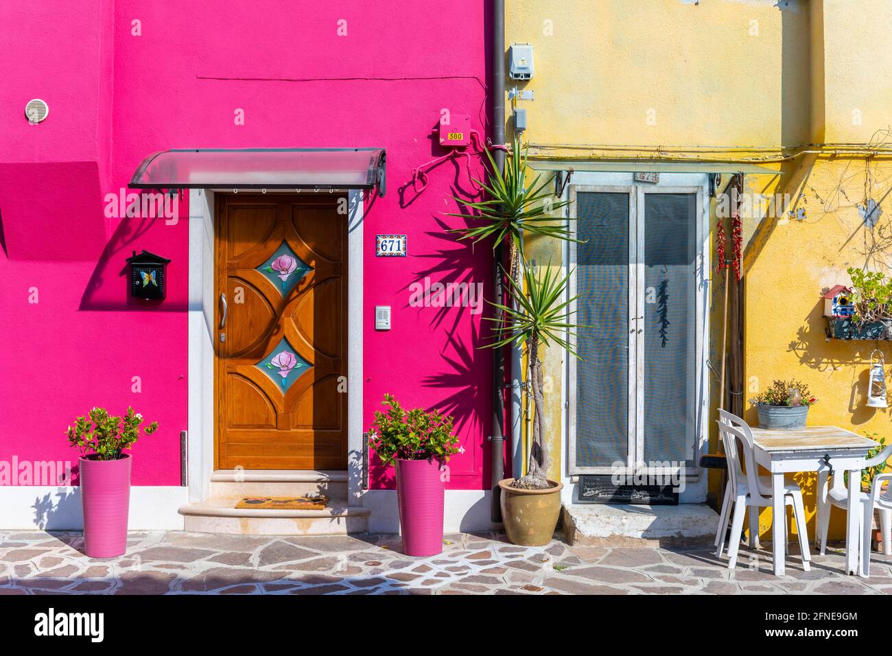 Two colorful houses, plants and table, colorful facade, Burano Island ...