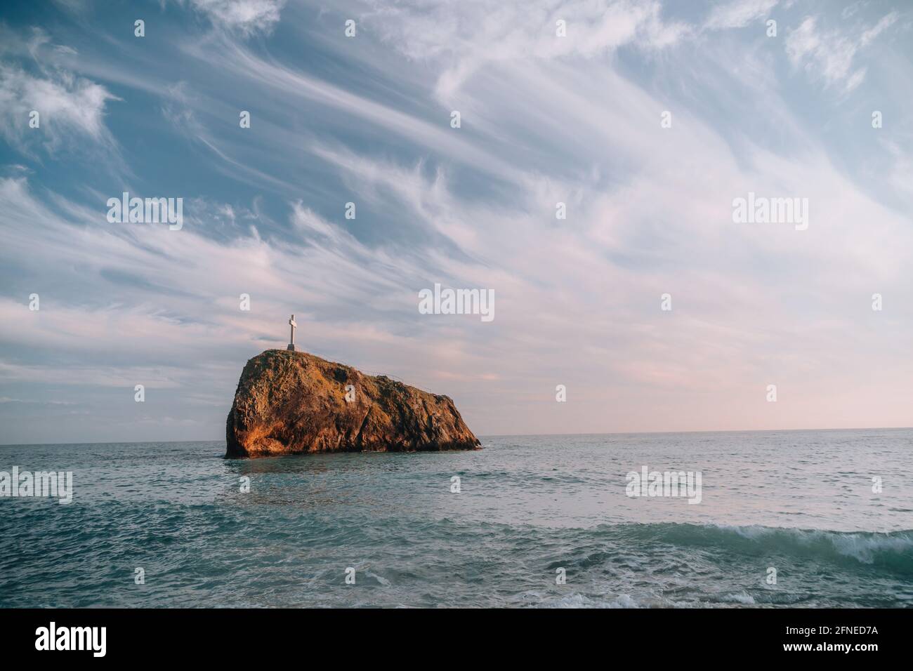 Bright sea sunset. The waves crash into the rock, lit by the warm ...