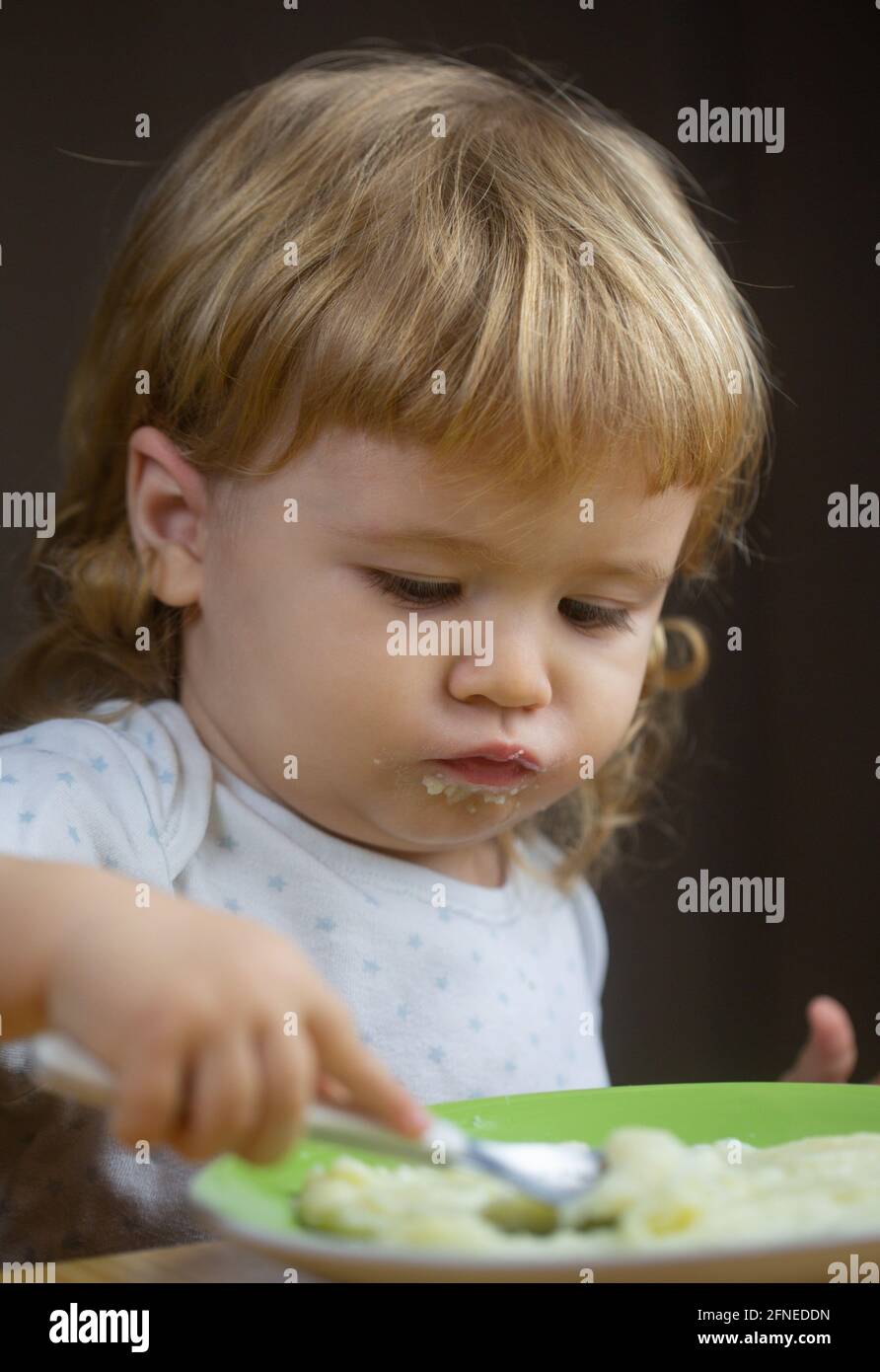 Kid baby with a spoon and a plate in the kitchen at home Stock Photo ...