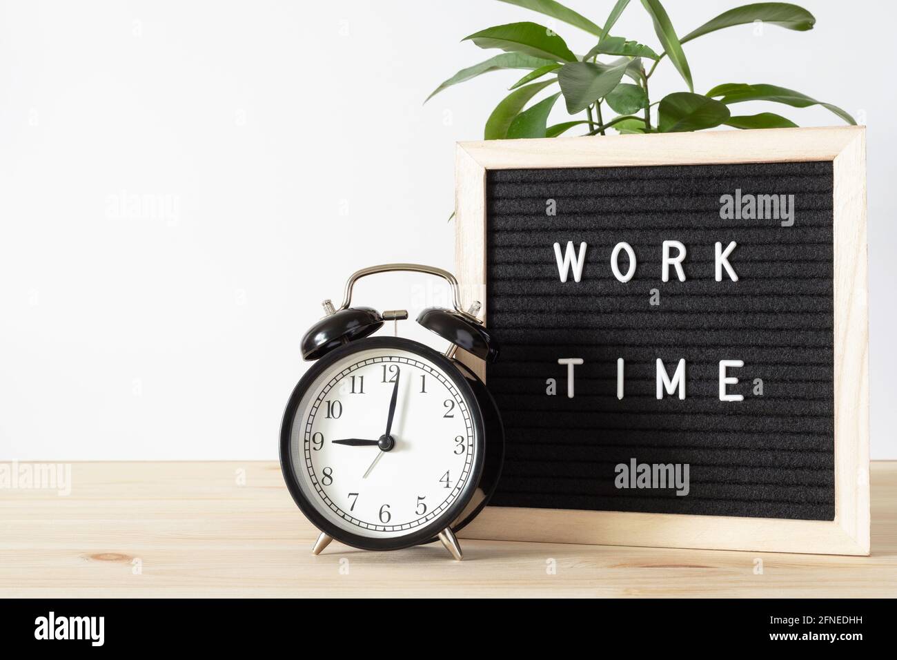 Classic vintage black alarm clock, board sign 'work time' and potted ...
