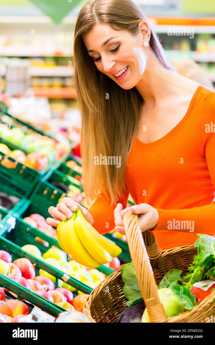 Woman in supermarket at the fruit shelf shopping for groceries, she is ...