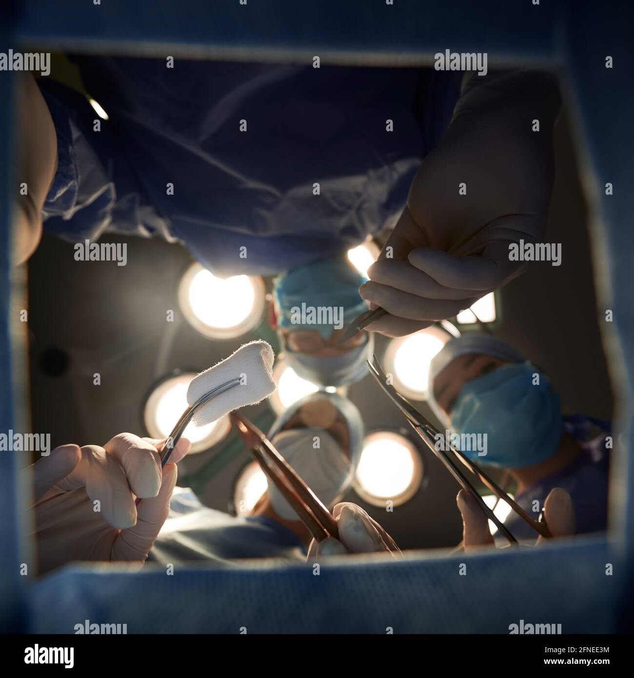 View from below of medical team holding scalpel, scissors and forceps ...