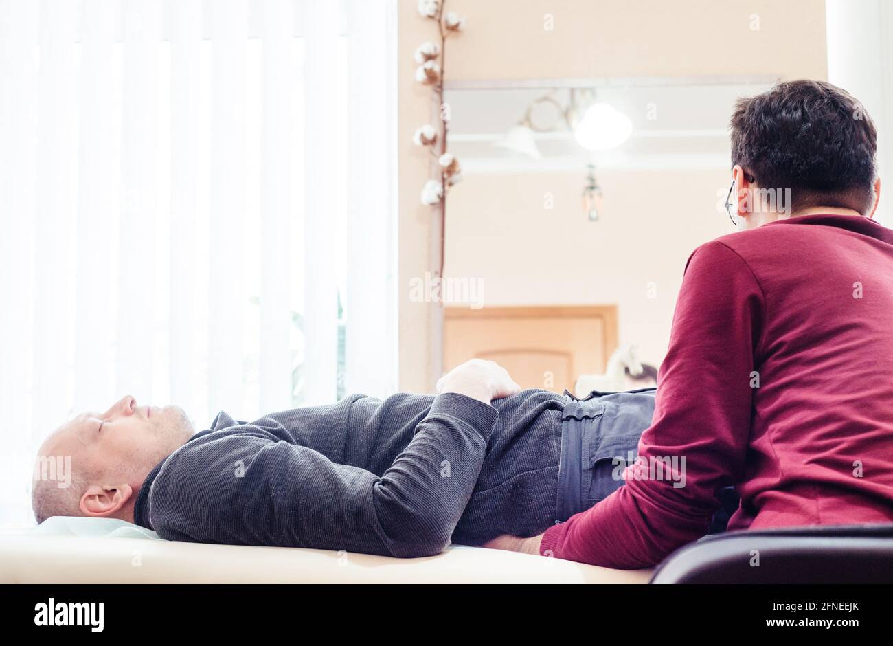 Craniosacral therapy practitioner giving a male patient CST osteopathic ...