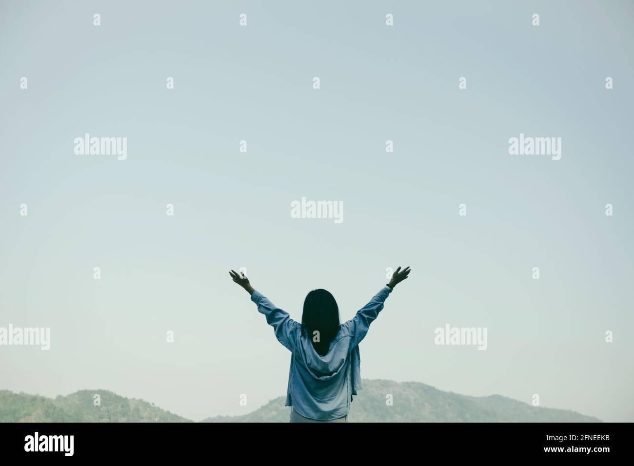 Woman rise hands up to sky freedom concept with blue sky and summer ...