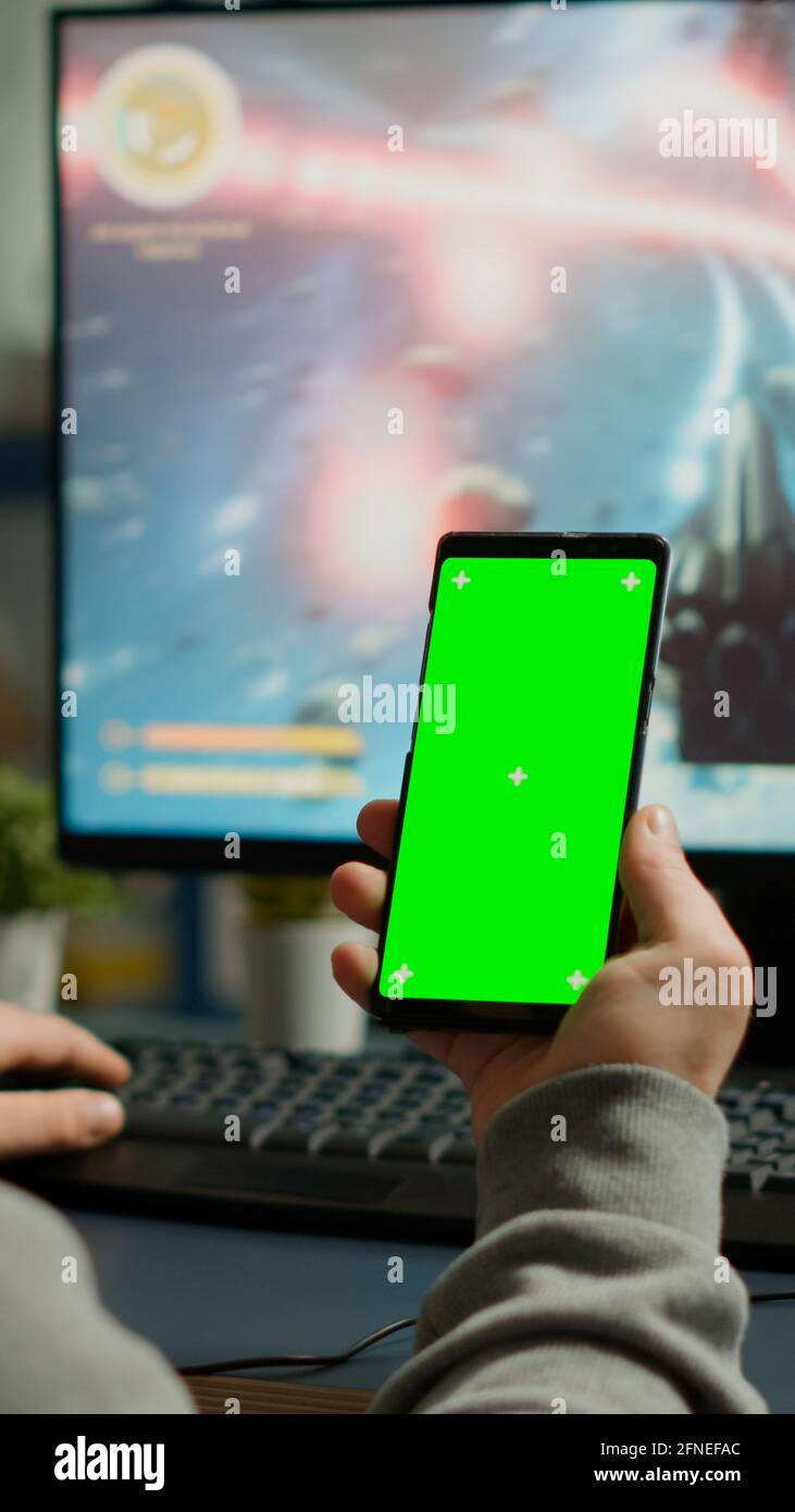 Concentrate gamer holding phone with green screen mock up chorma key ...