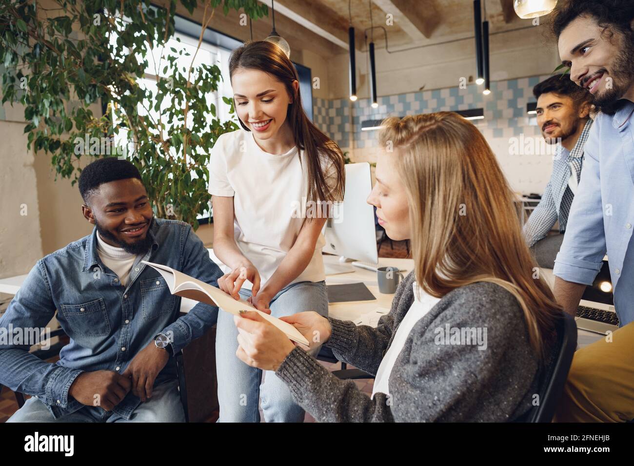 Group of young business people discussing documents during meeting in ...