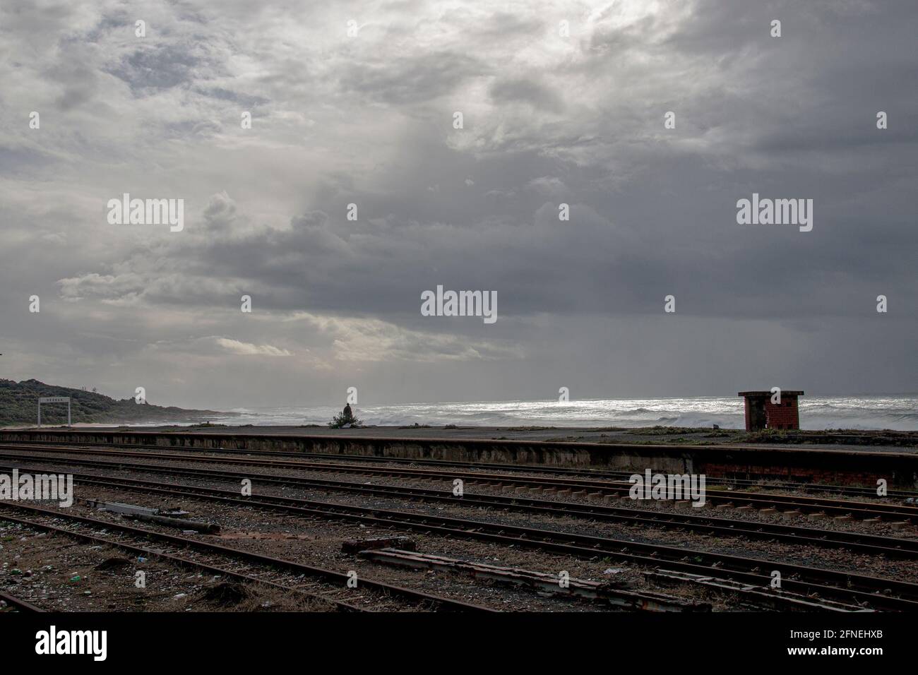 Disused railway tracks with heavy cloudy sky and sea Stock Photo - Alamy