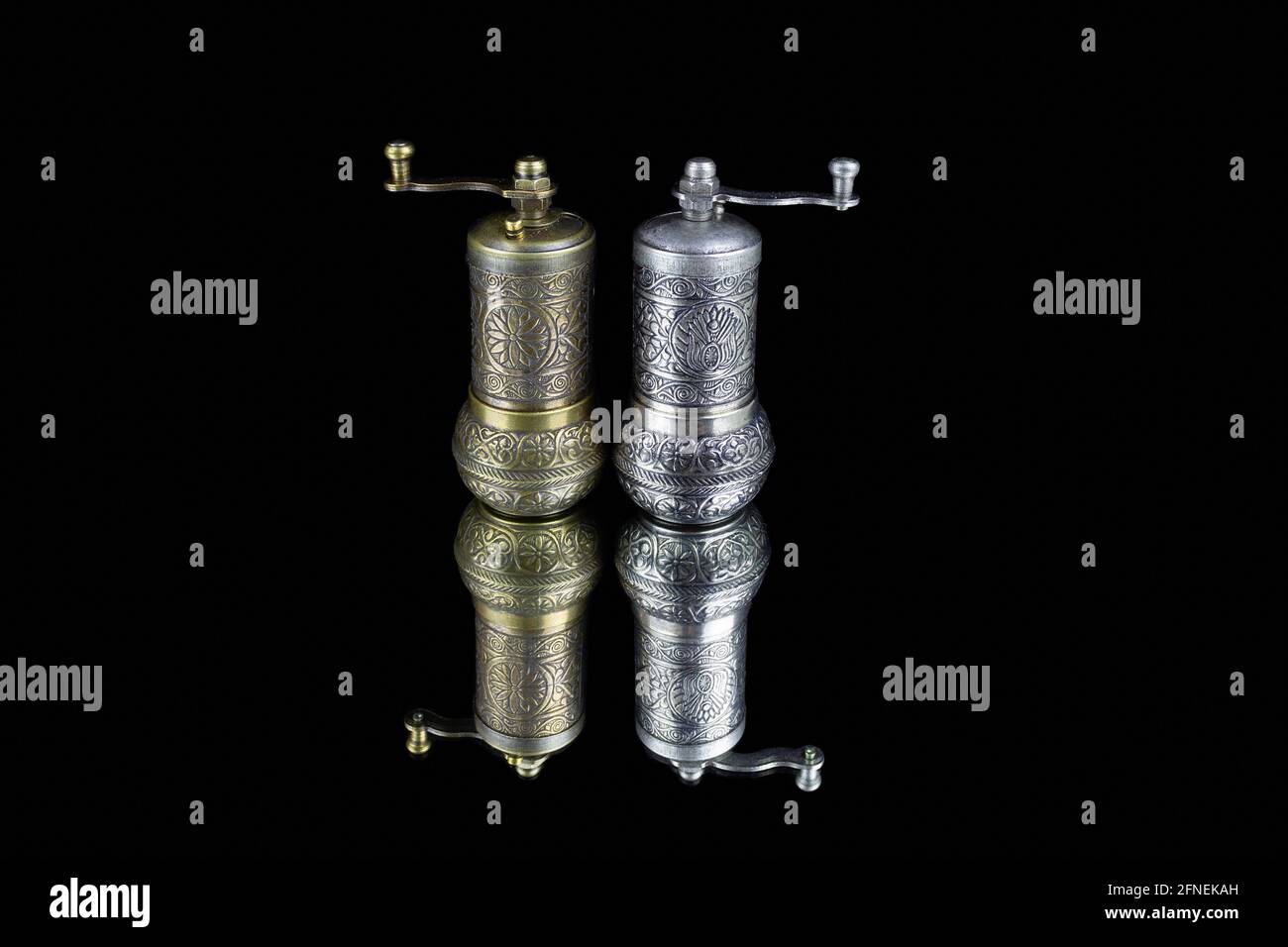 Two patterned silver pepperpots on black reflective surface Stock Photo ...