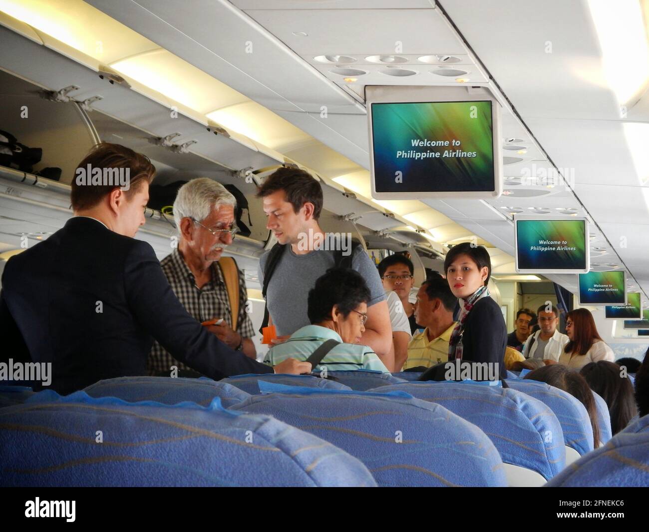 Passengers walking on the isle of an airplane cabin in Manila ...