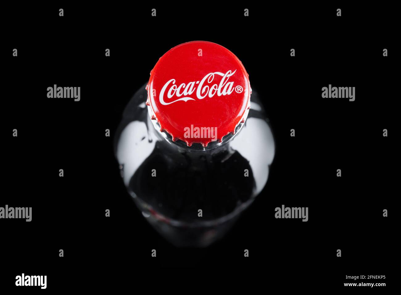 Glass bottle of coca cola with red cap, top view on black background ...