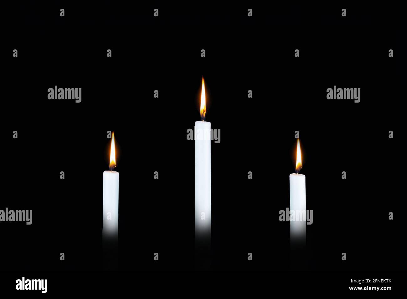 Three burning candles fading into blackout on black background. Medium ...