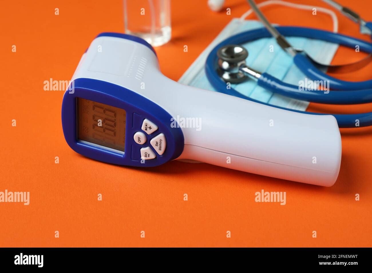 Medical tools and thermometer gun on orange background Stock Photo - Alamy
