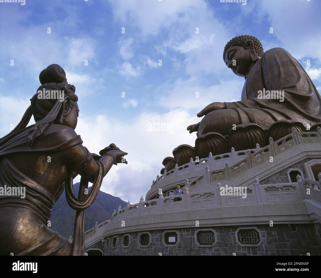 The statue of a sacrificing girl in front of the giant Buddha statue of ...