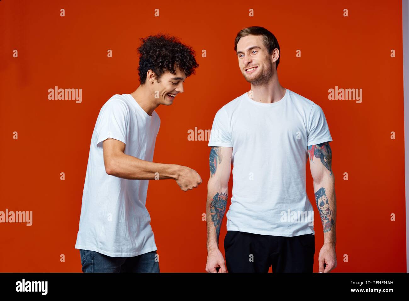 two friends in white t-shirts stand side by side isolated background ...