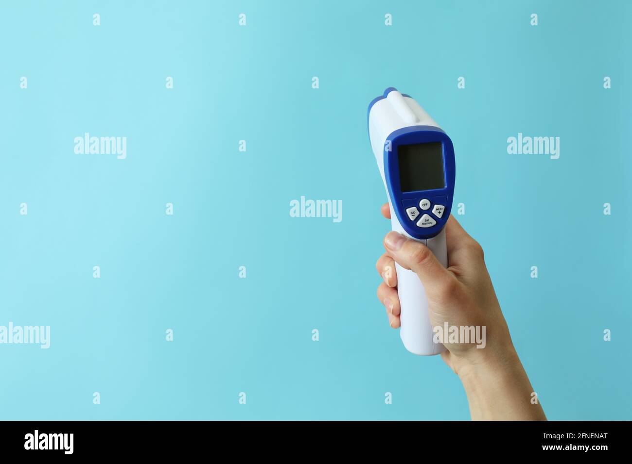 Female hand hold thermometer gun on blue background Stock Photo - Alamy