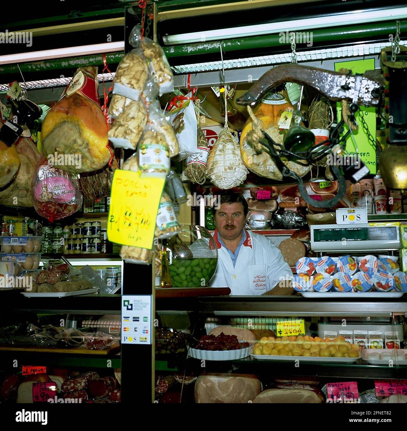 A salesman behind the Parma ham displays in deli. [automated ...
