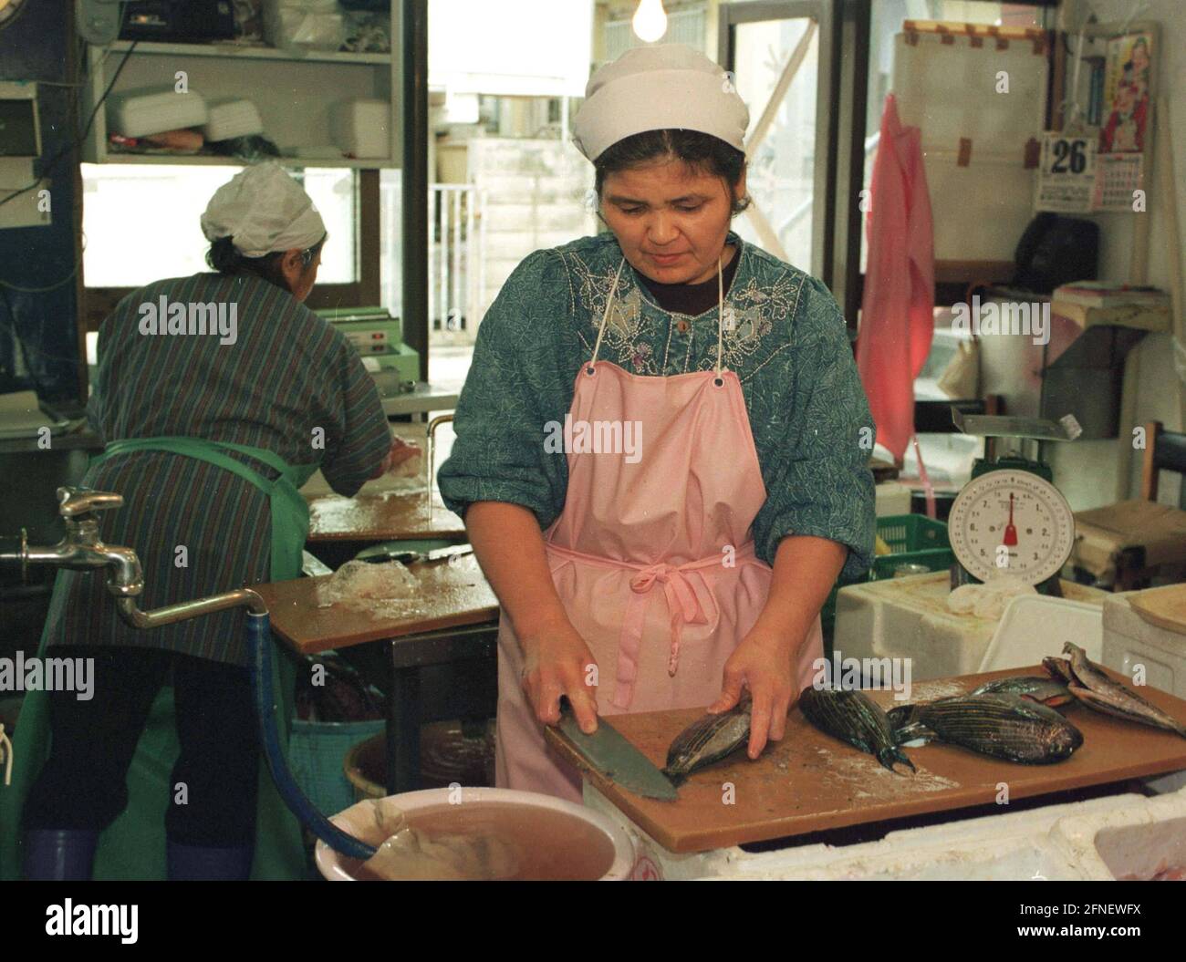 Woman with apron processing fish in a shop in Naha, Okinawa. [automated ...