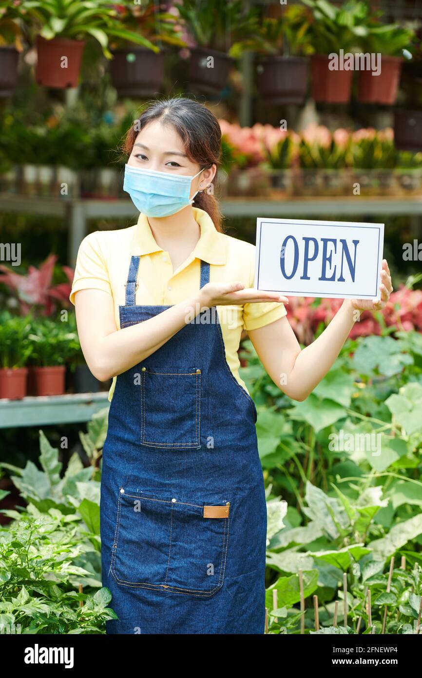 Lovely young woman wearing protective mask when inviting customers in ...