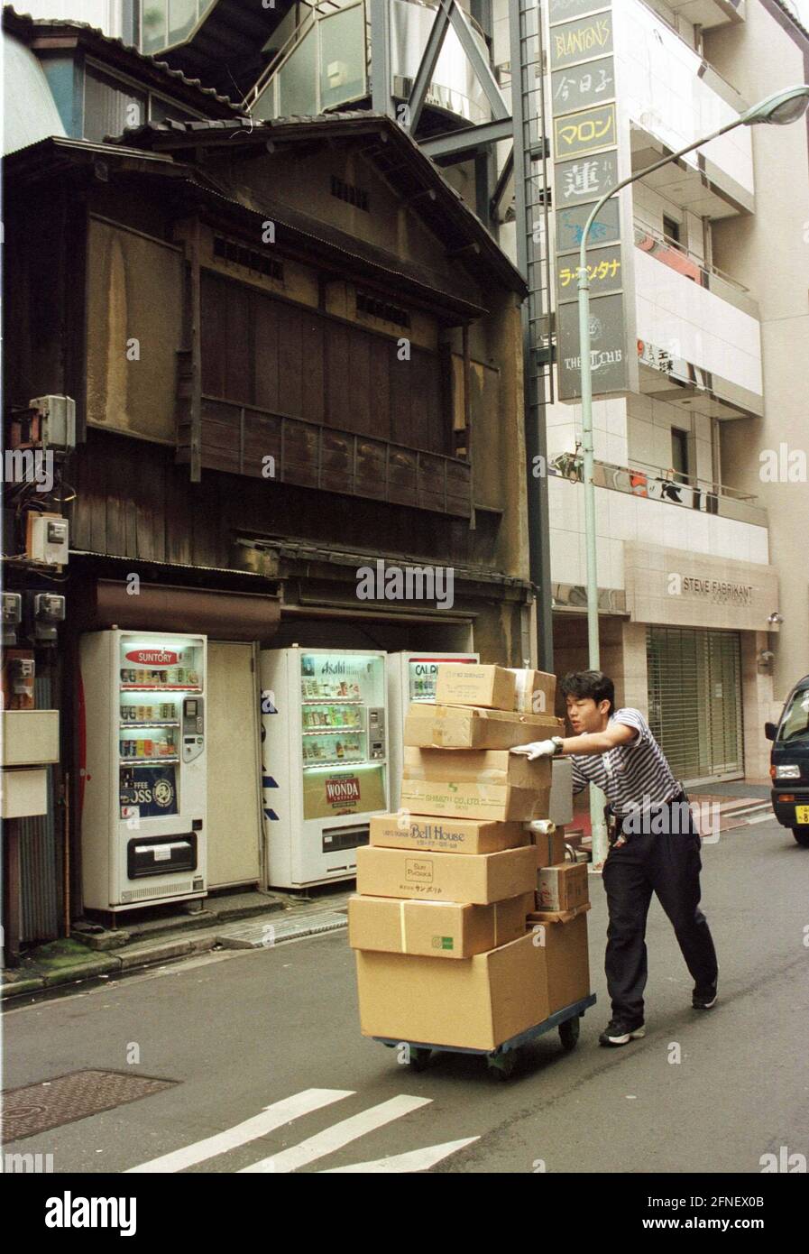Japanese man transports a cart heavily loaded with boxes on a street in ...