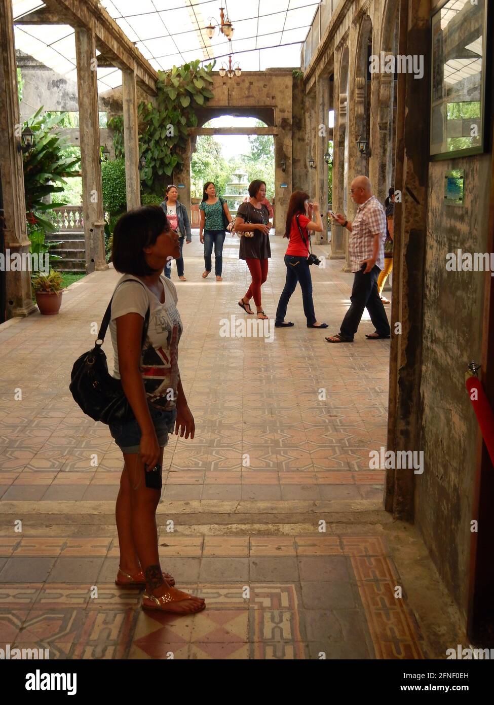 Woman looks at a painting while tourists visit the The Ruins, Bacolod ...