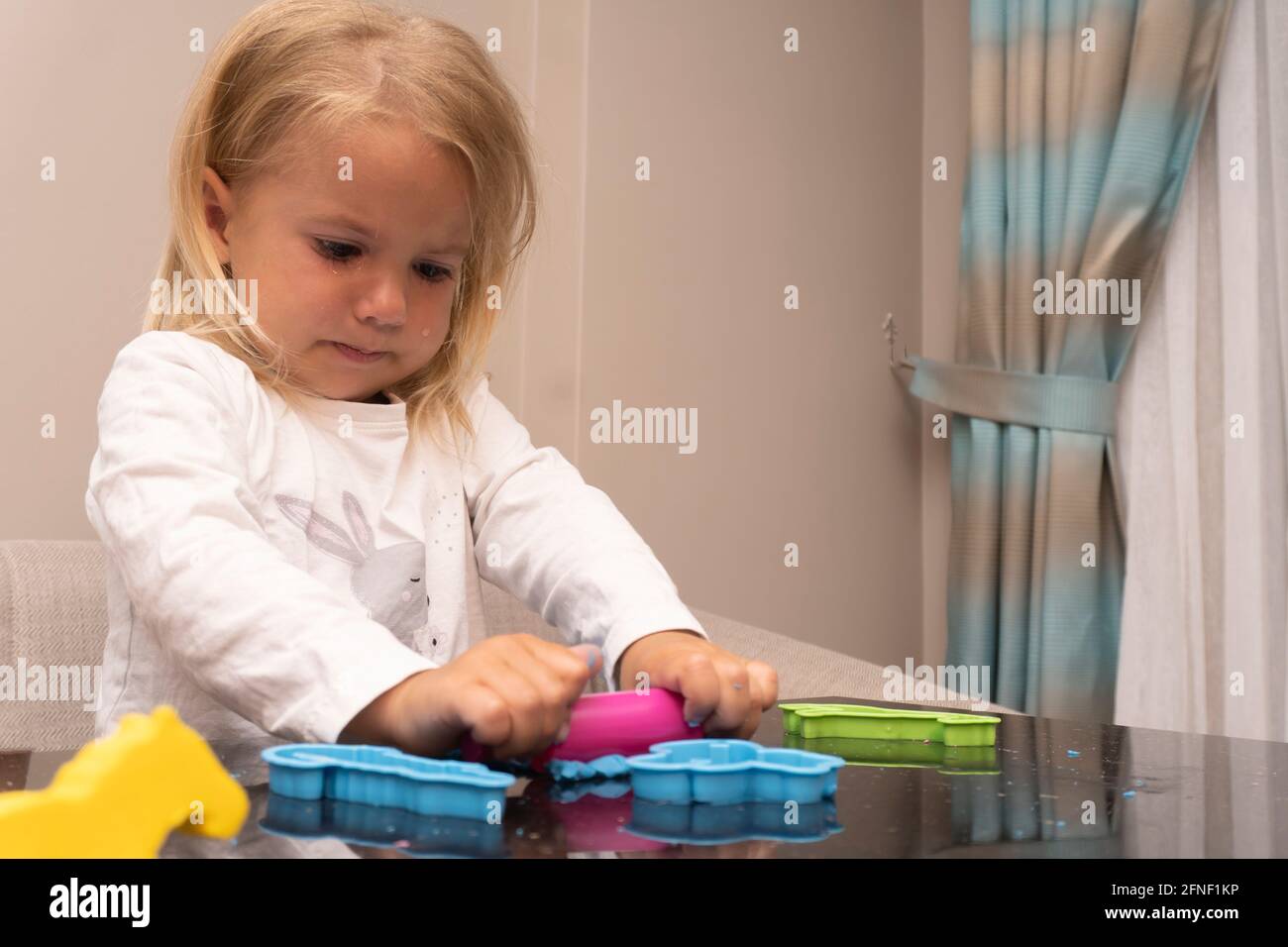 Crying kid plays with colorful playdough Stock Photo - Alamy
