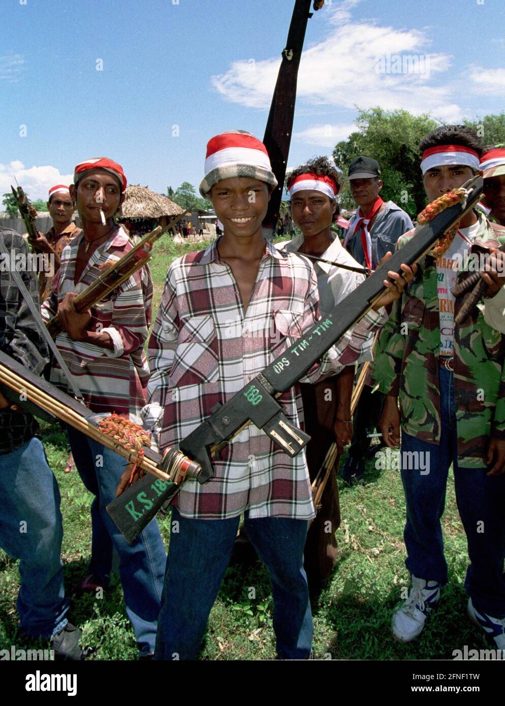 Armed Aitarak fighters wearing red and white headbands at a gathering ...