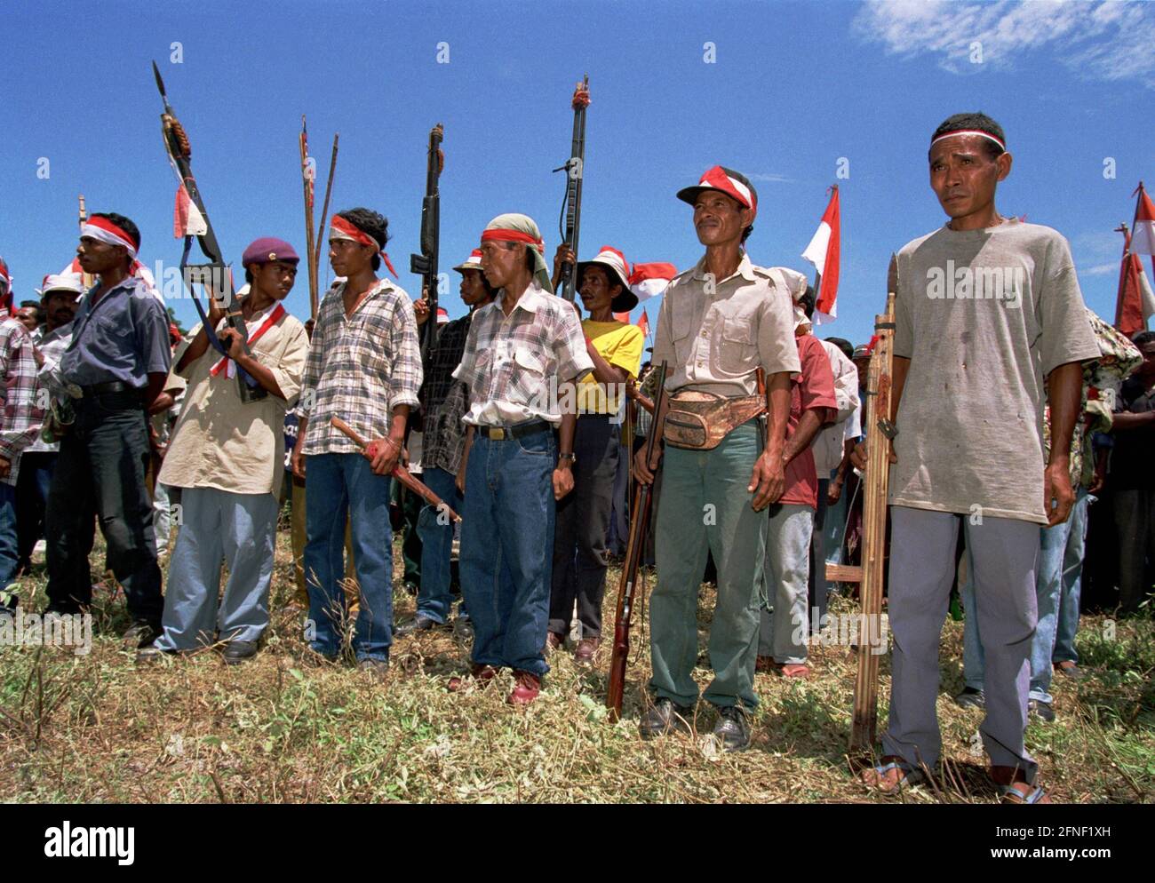 Armed Aitarak fighters wearing red and white headbands at a gathering ...