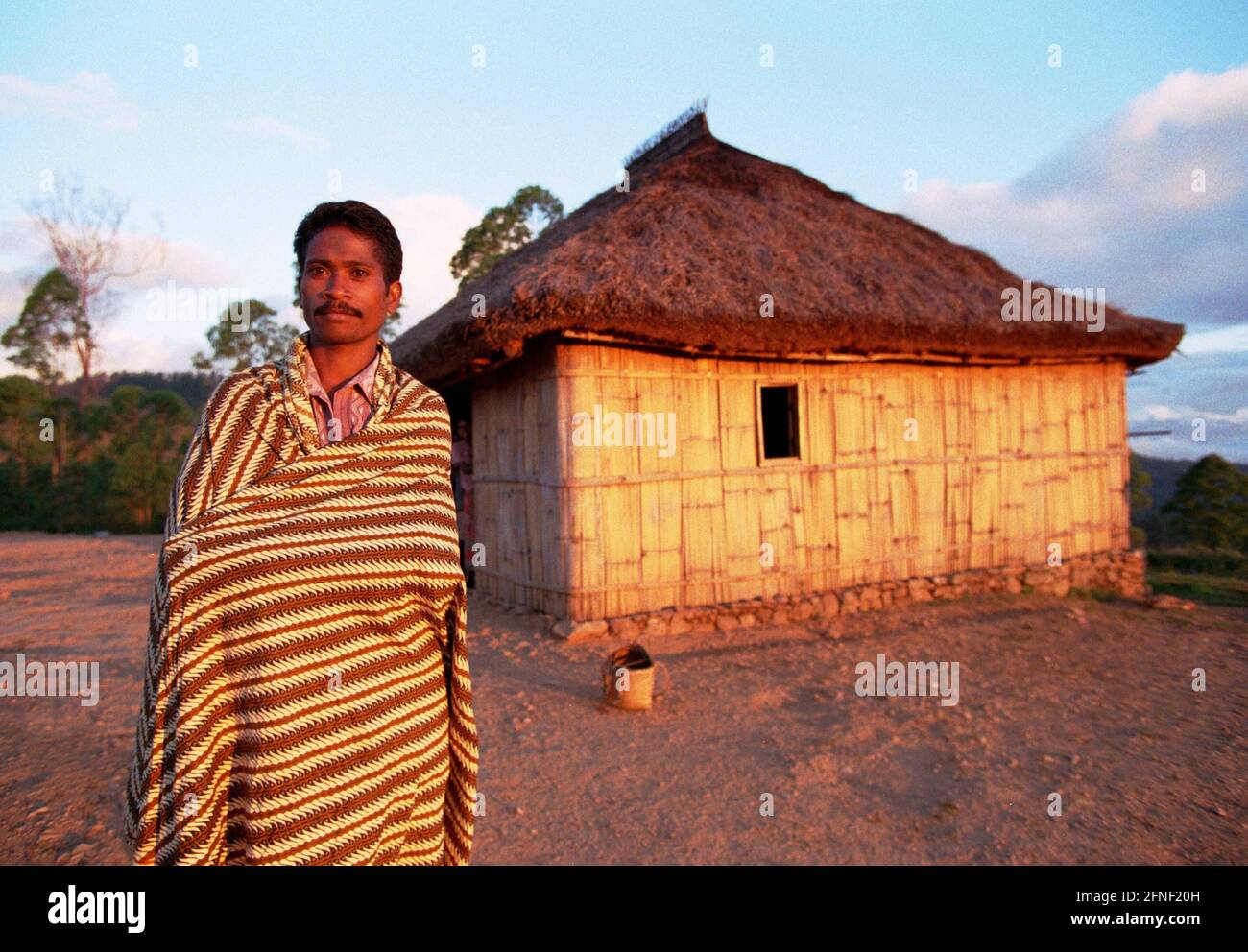 Farmer in the evening light in front of his house in the Ermera ...