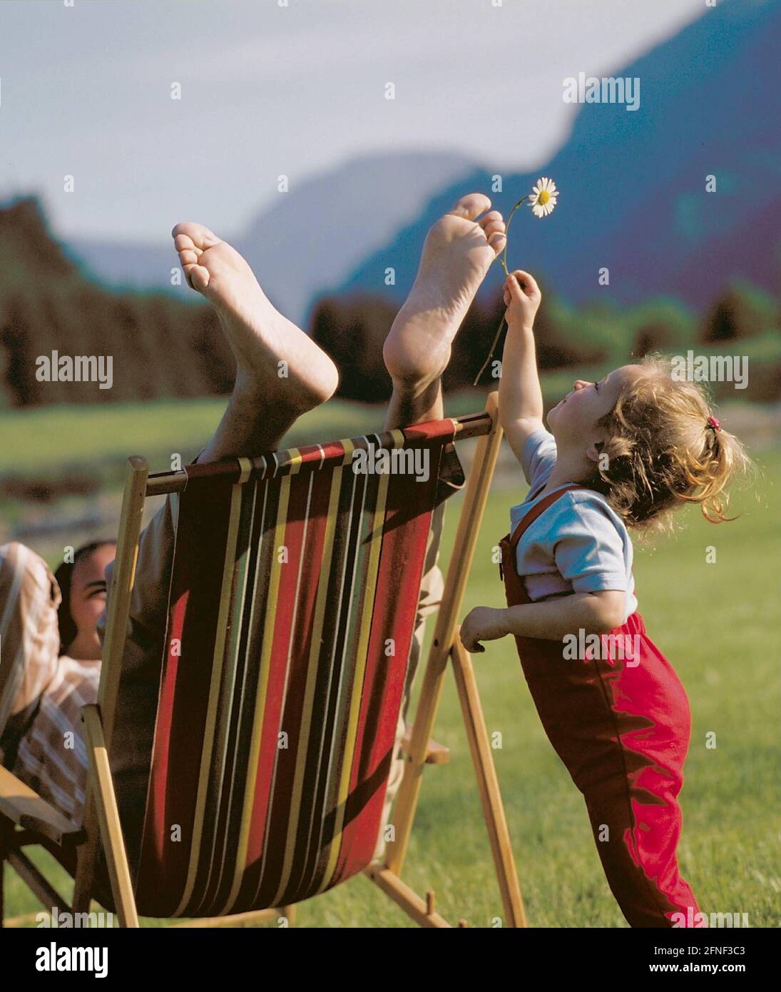 A small child puts a daisy between his father's toes. [automated ...